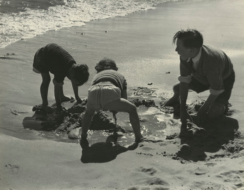 Tre bambini che giocano con la sabbia in spiaggia